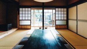 Um quarto japonês tradicional com tatames, uma mesa baixa, portas deslizantes e um lustre.