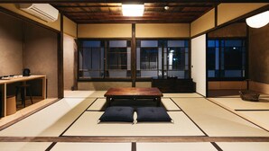 Um quarto japonês tradicional com tatames, uma mesa baixa e portas deslizantes.