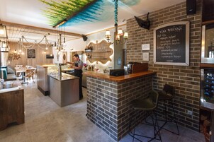 Uma área de bar com balcão de tijolos, luminárias pendentes e um menu em lousa.