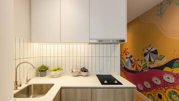 Uma cozinha moderna com armários brancos, uma pia de aço inoxidável e um mural colorido na parede.
