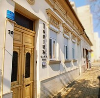 A building with ornate architectural details, a sign reading "INDIUM CITY", and a blue sign above the door.