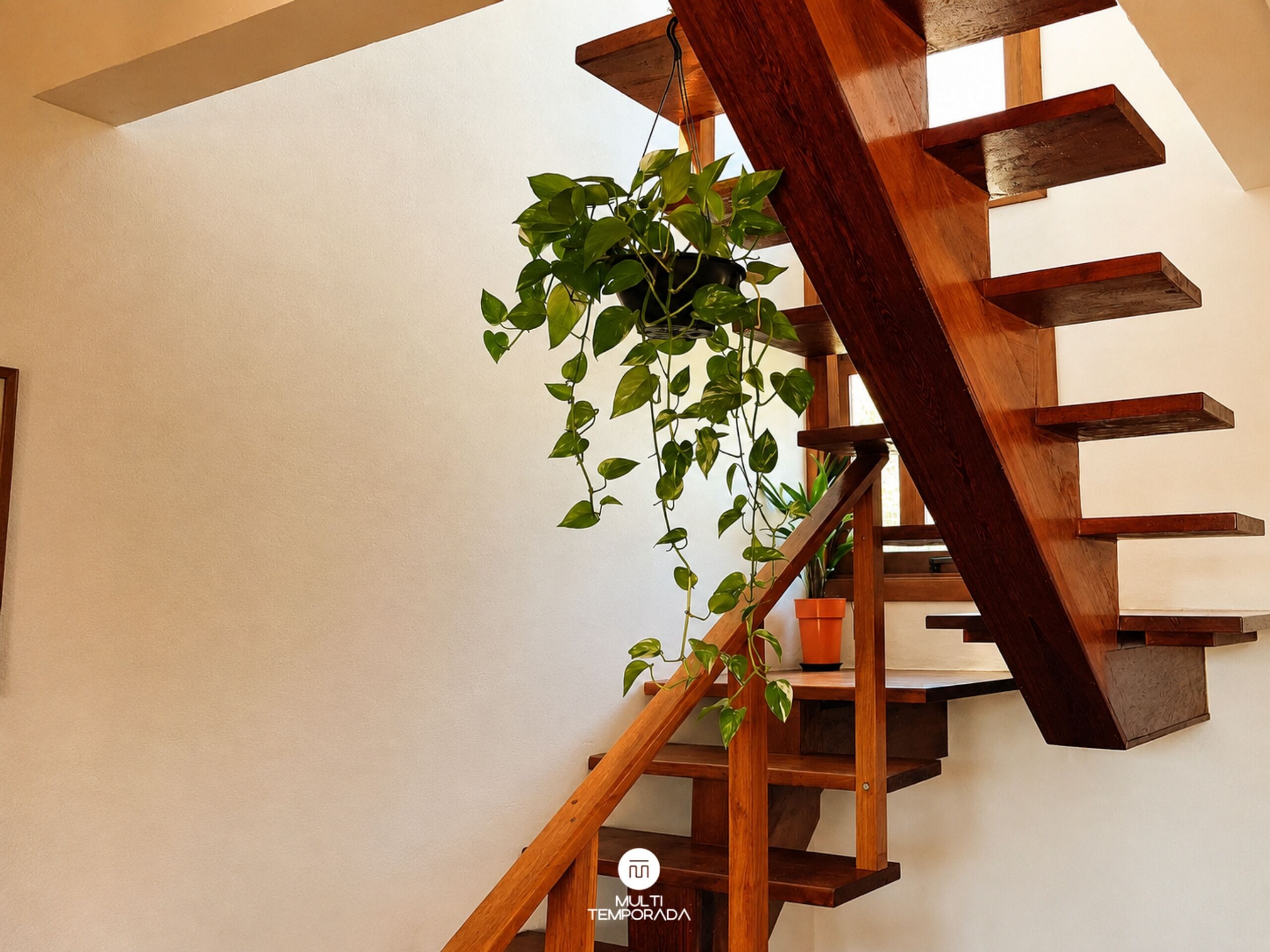 Uma escada de madeira com um vaso de planta pendurado no corrimão.
