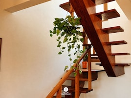 Uma escada de madeira com um vaso de planta pendurado no corrimão.