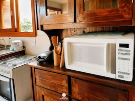 Uma cozinha com micro-ondas, fogão e armários de madeira.