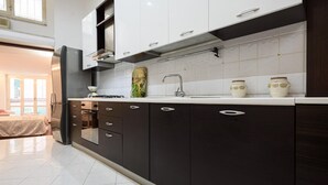 Cozinha moderna com armários escuros, geladeira de aço inoxidável e painel de azulejos.