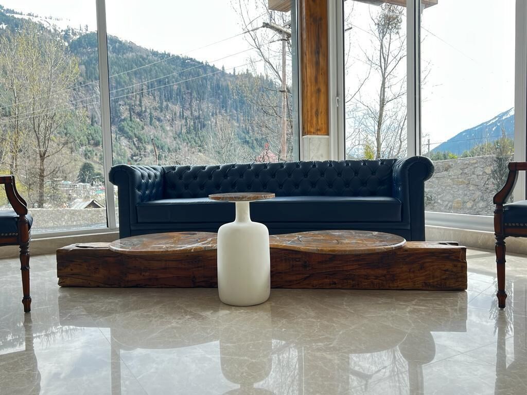Uma sala de estar moderna com um sofá azul escuro, um vaso branco e uma mesa de centro de madeira.
