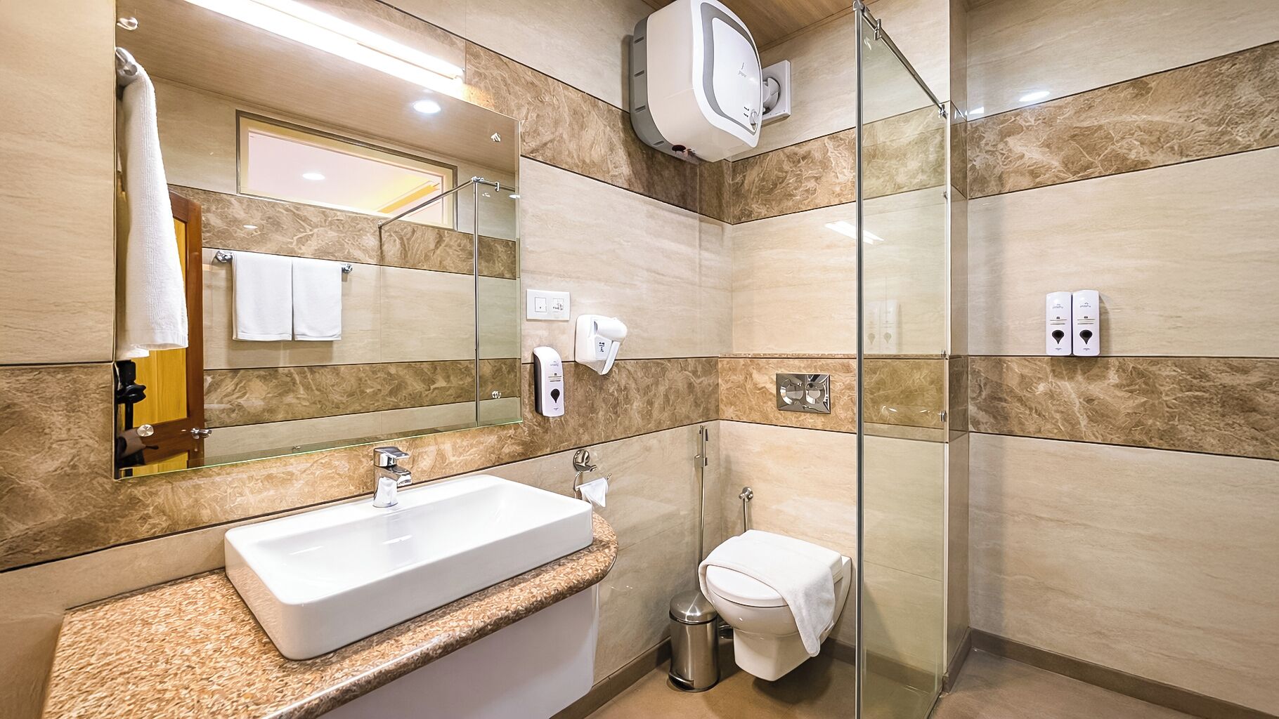 Uma casa de banho moderna com um espelho grande, uma pia, uma sanita e zona de duche.