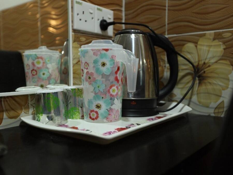 Uma bancada de cozinha com uma cafeteira, uma chaleira e duas xícaras com padrão floral.