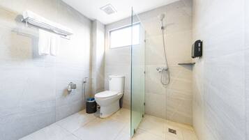Uma casa de banho moderna com cabine de duche em vidro, sanita e porta-toalhas.