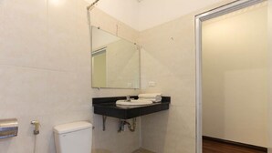 Casa de banho com sanita, lavatório, espelho e zona de duche.