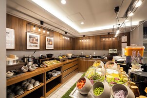 Cozinha moderna com armários de madeira, eletrodomésticos de aço inoxidável e diversos alimentos expostos no balcão.