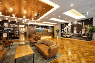 Um lobby moderno com piso de madeira, sofás de couro e um balcão de recepção.