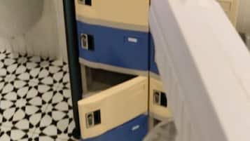 Uma fileira de armários azuis e bege em um banheiro público.