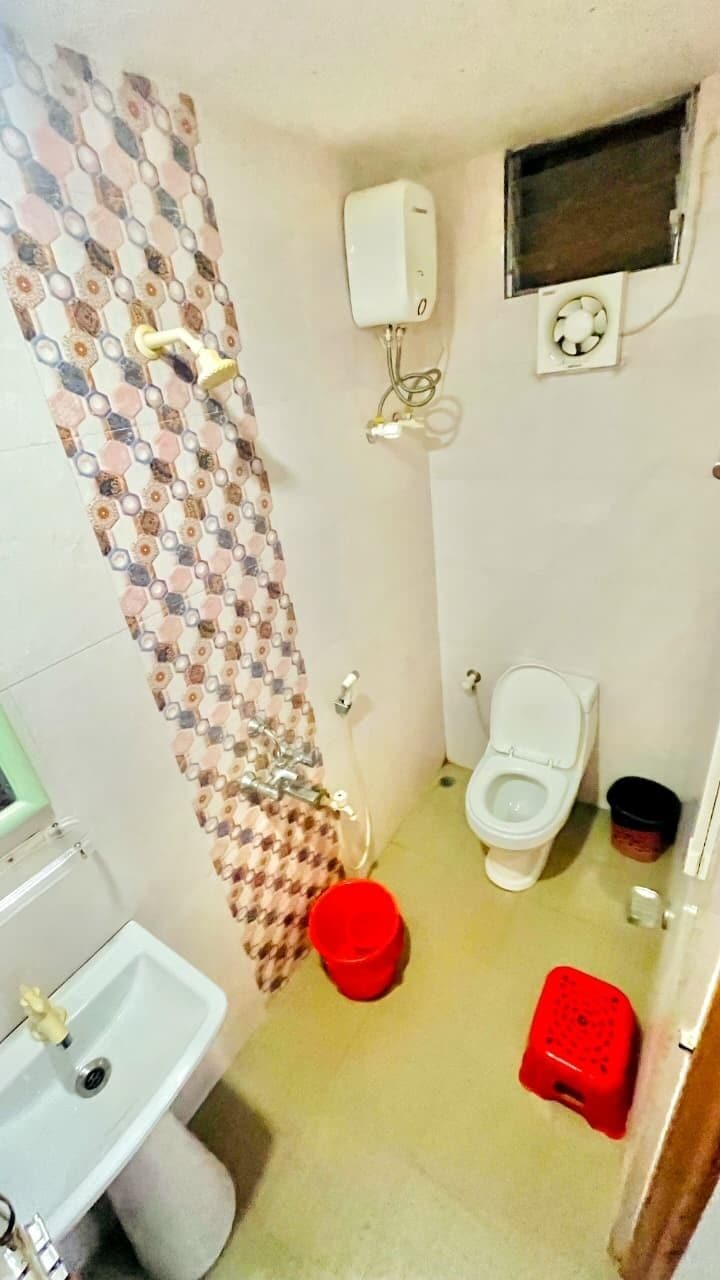 Um banheiro pequeno com vaso sanitário, pia e chuveiro. Há uma janela com vista para o exterior.