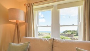 Quarto com sofá, luminária e vista para o exterior através de duas janelas.