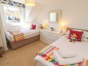 Quarto com duas camas, cômoda, espelho e janela com vista para prédios.