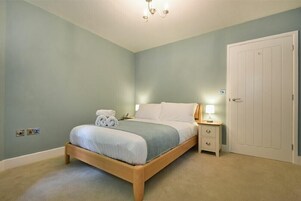 Quarto com cama, mesa de cabeceira, abajur e guarda-roupa.