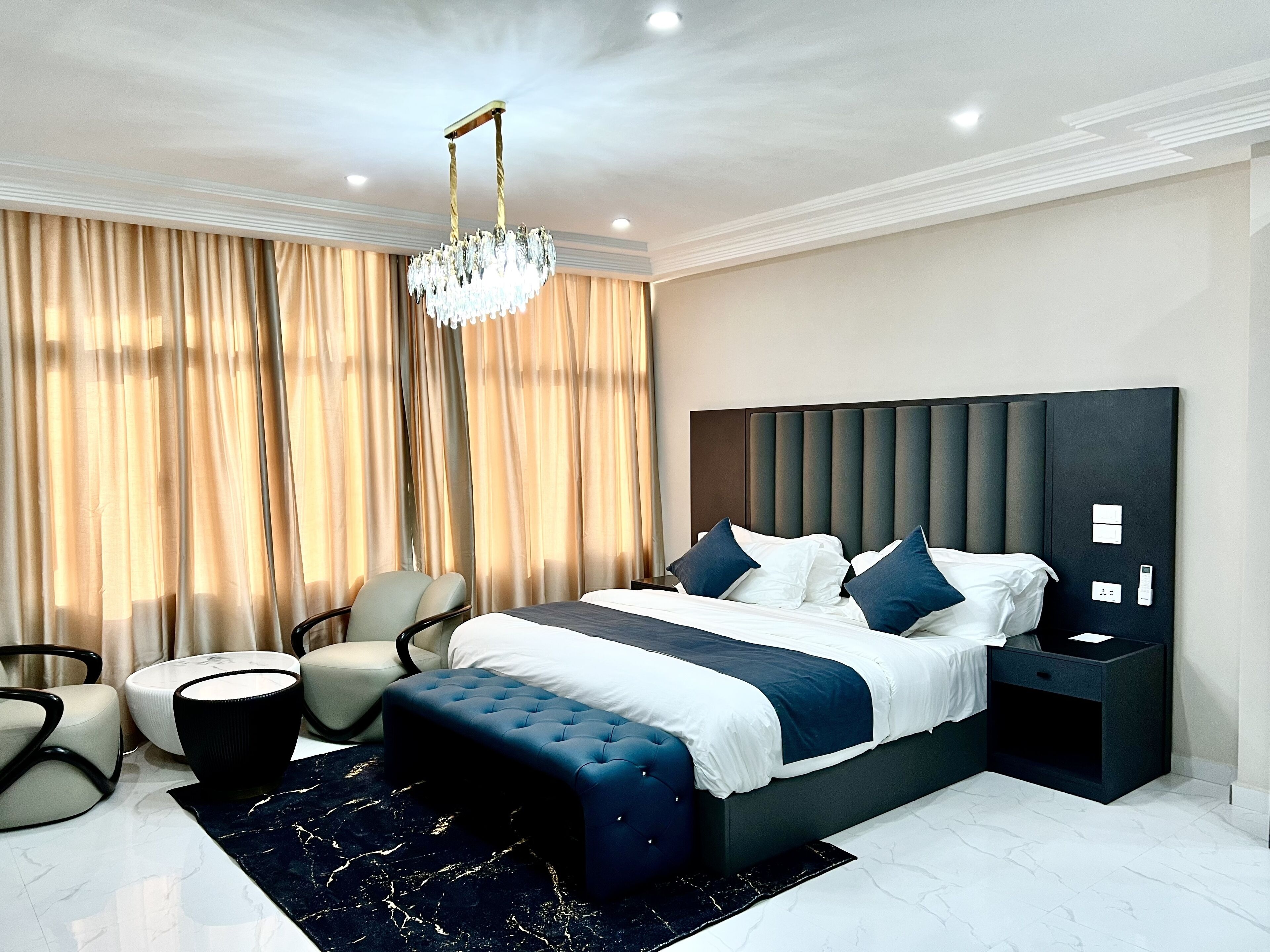 Quarto moderno com uma cama grande, um candelabro e vista para a cidade.