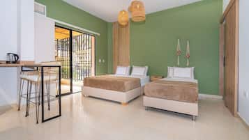 Quarto com duas camas, uma mesinha e uma cadeira. Há uma porta de correr que dá para uma área externa.