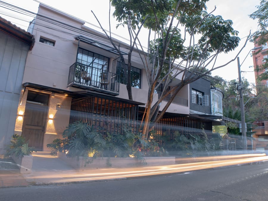 Um edifício moderno com varandas, entrada com portão e um jardim bem cuidado.