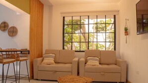 Sala de estar com dois sofás, uma mesinha e um espaço de jantar com cadeiras.
