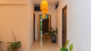 Um corredor com piso ladrilhado, plantas em vasos e luminárias pendentes.