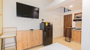 Cozinha moderna com frigorífico embutido, micro-ondas e televisor de ecrã plano fixado na parede.