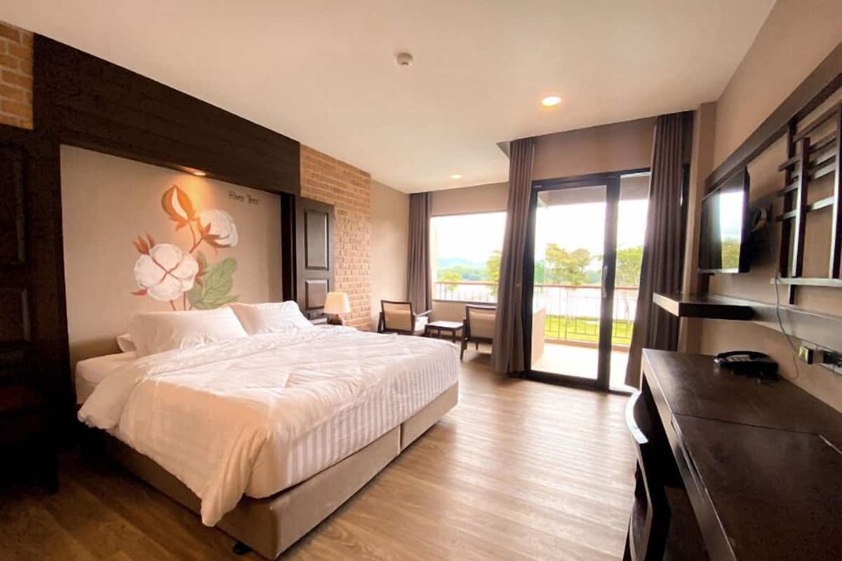 Quarto de hotel moderno com uma cama grande, uma escrivaninha, uma televisão e uma varanda com vista.