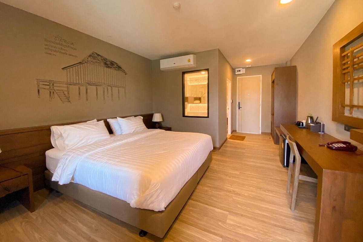 Quarto de hotel com cama, escrivaninha e espelho.