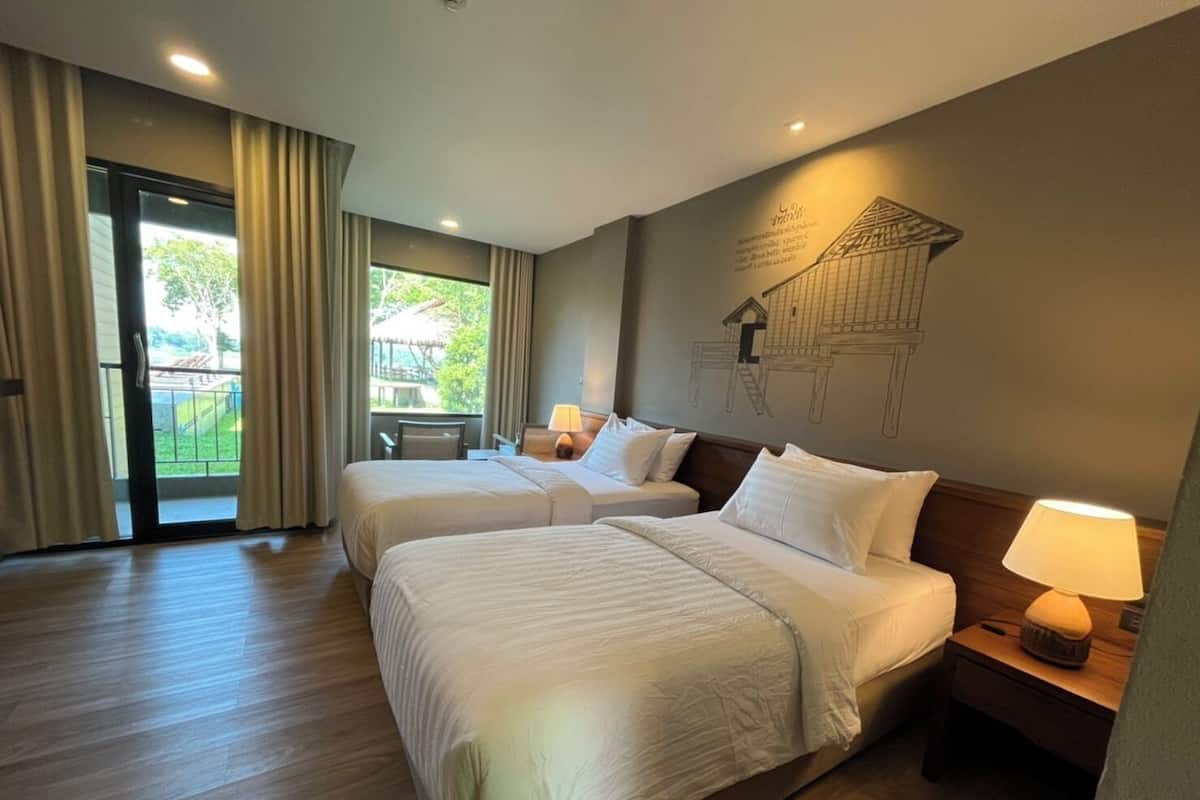 Quarto de hotel com duas camas, varanda e um mural na parede.
