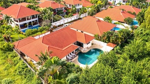 Um resort com vários edifícios, cada um com telhados de telha vermelha e cercado por vegetação exuberante.