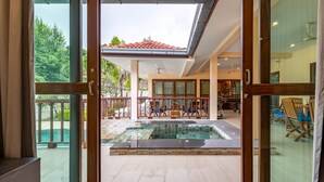Amplo espaço interno com piscina em vidro, deck de madeira e vista para o exterior.