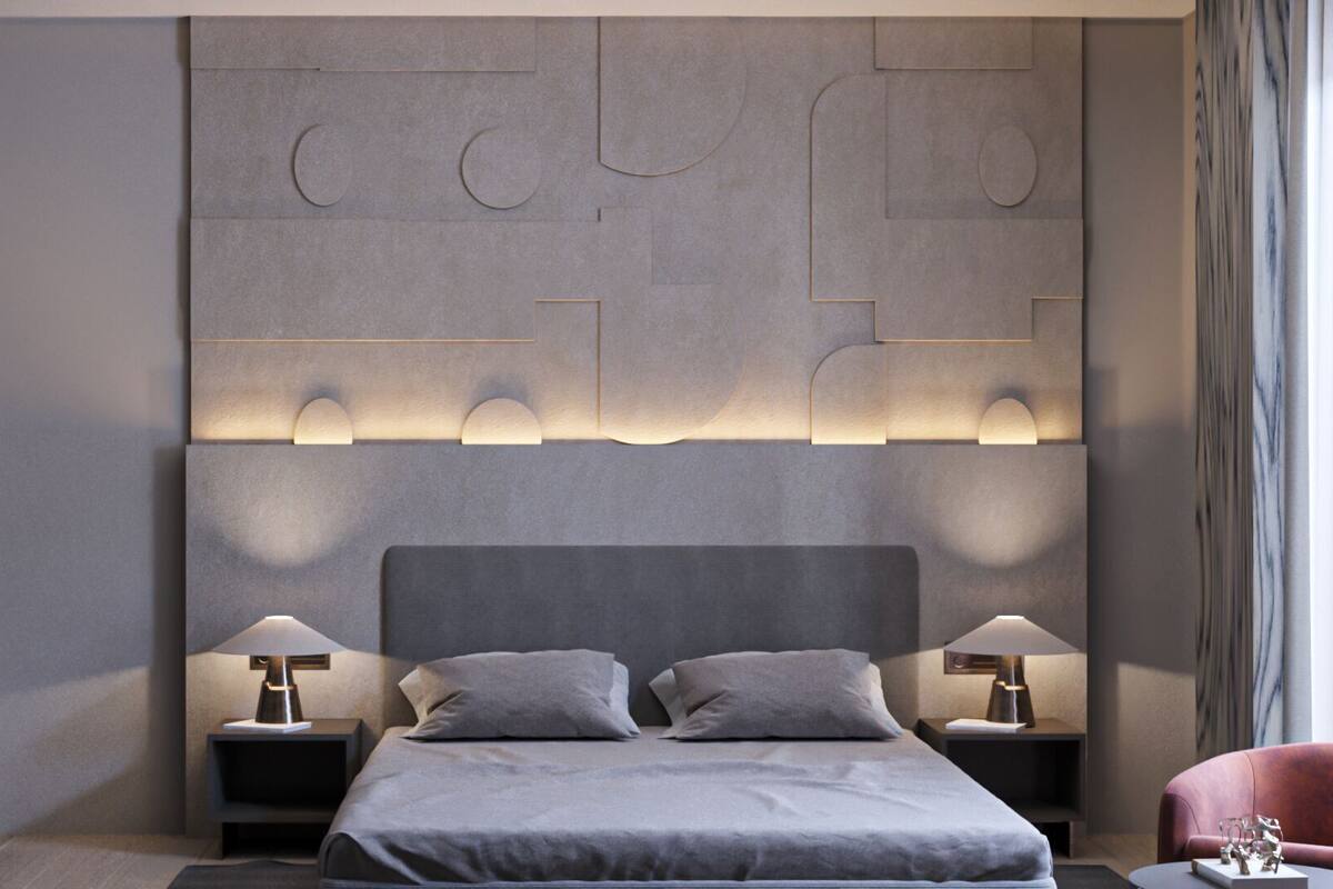 Quarto moderno com cabeceira cinza, duas mesas de cabeceira com luminárias, guarda-roupa e uma poltrona vermelha.
