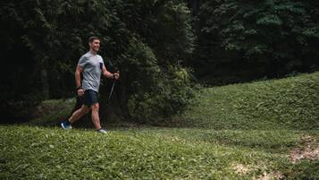 Uma pessoa caminhando em uma área gramada ao ar livre, com árvores ao fundo.