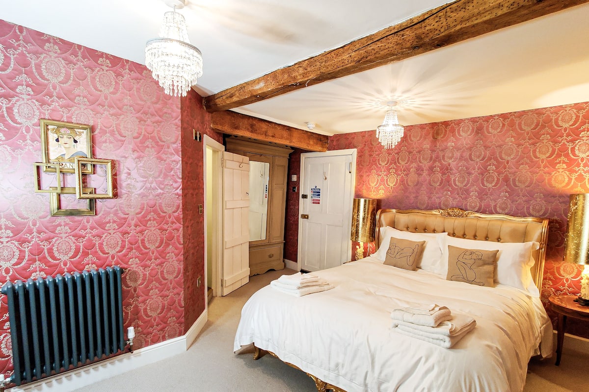 Quarto com uma cama grande, uma cômoda, um radiador e um candelabro.