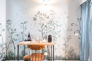 Uma sala de jantar com uma mesa posta para dois, uma cadeira e uma parede com painel decorativo de bambu.