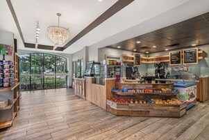 Interior moderno de café com balcão de madeira, área de estar e vista para o exterior.