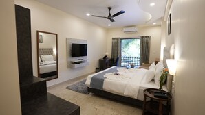 Quarto de hotel moderno com uma cama grande, uma TV de tela plana, um ventilador de teto e um aparelho de ar condicionado.