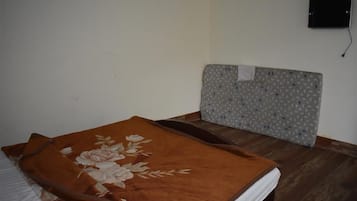 Quarto com cama, cabeceira de madeira e televisão presa à parede.
