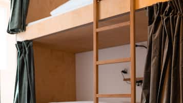 Uma cama beliche com escada, cabeceira de madeira e cortinas.