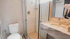 Casa de banho moderna com cabine de chuveiro em vidro, sanita branca e lavatório de mármore.