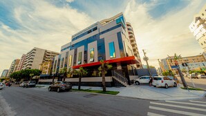 Um hotel moderno com entrada imponente, vários andares e vista clara do céu.
