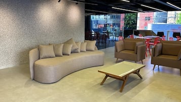 Uma área de estar moderna com um sofá curvo, duas poltronas e uma mesinha.