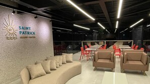 Um lobby de hotel moderno com um sofá curvo, cadeiras vermelhas e uma mesa branca.
