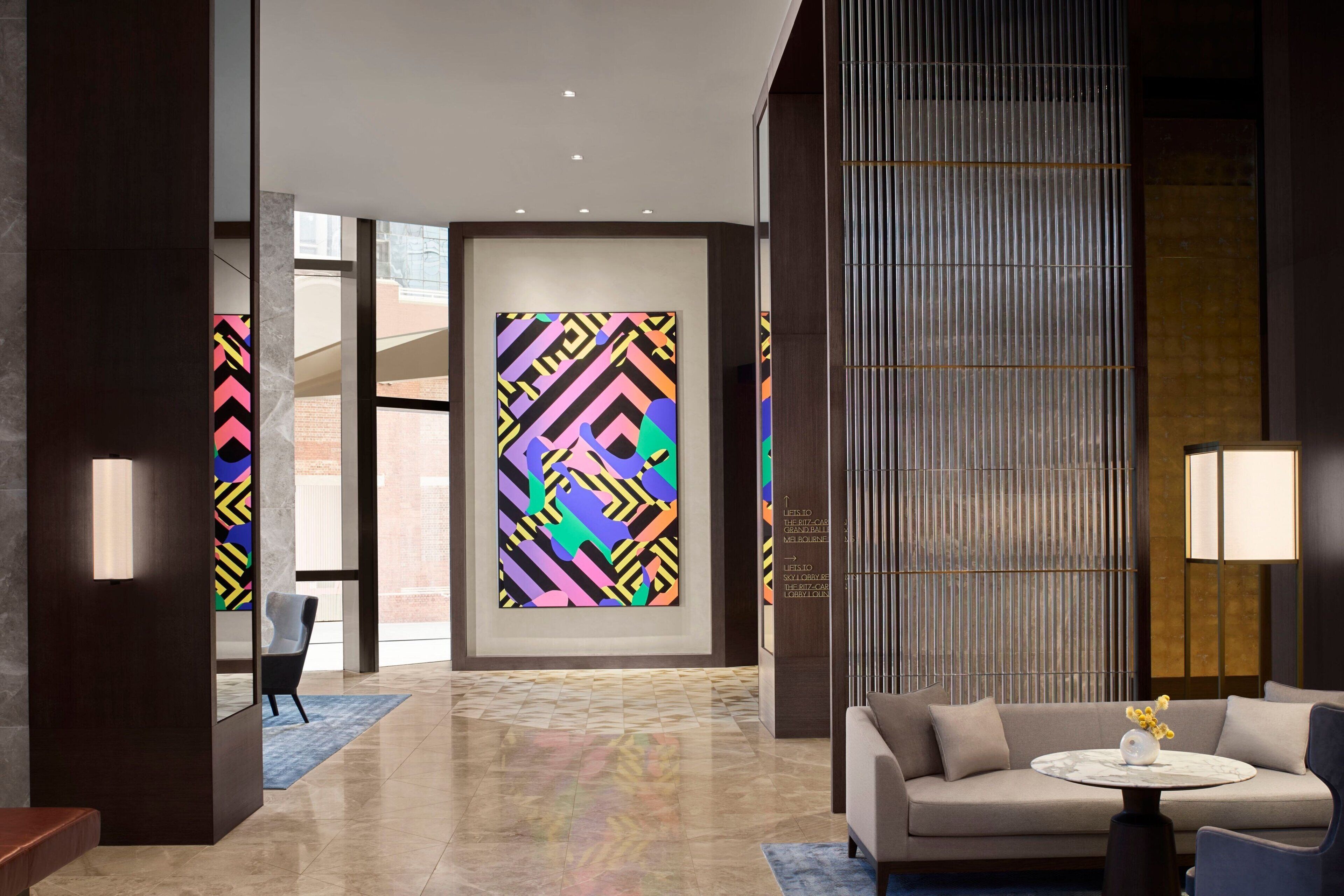 Um lobby moderno com uma grande obra de arte abstrata, um sofá e uma mesa de centro.