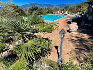 Área de piscina com espreguiçadeiras, um poste de luz e vista para montanhas.