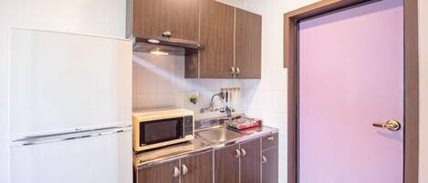 Uma cozinha compacta com micro-ondas, torradeira e pia.