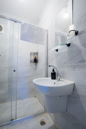 Um polibã, um chuveiro fixo, um secador de cabelo, chinelos 