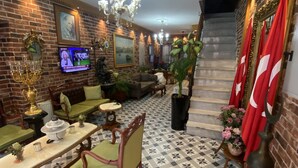 Uma área de estar ampla, com piso estampado, assentos confortáveis, televisão e escada que leva a um andar superior.
