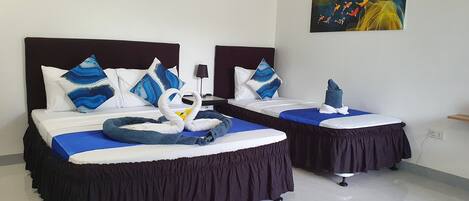 Duas camas de casal com roupa de cama azul e branca combinando, saias escuras e adornos de cisnes.